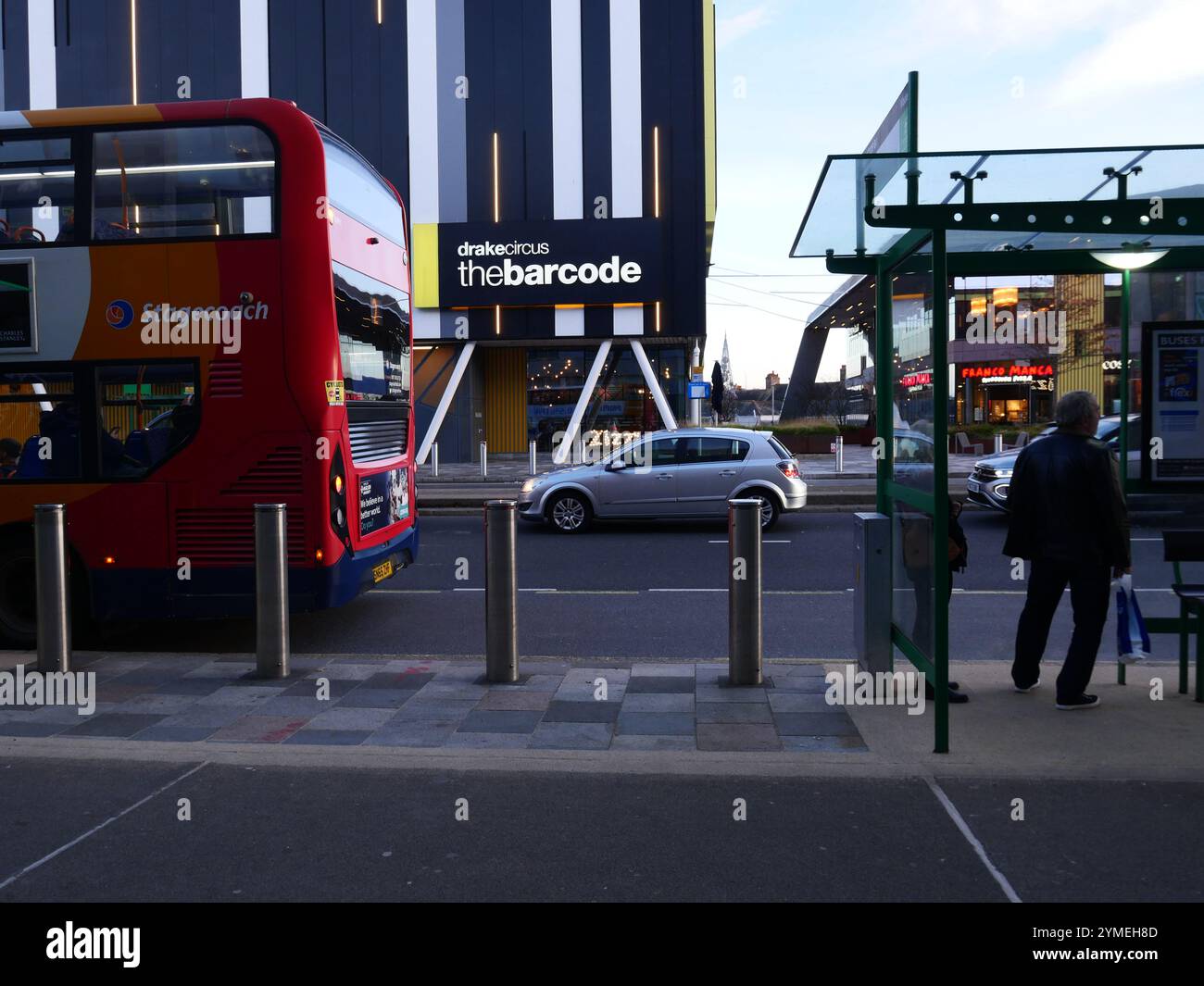 City street with man waiting at a bus stop. Plymouth, UK Stock Photo ...