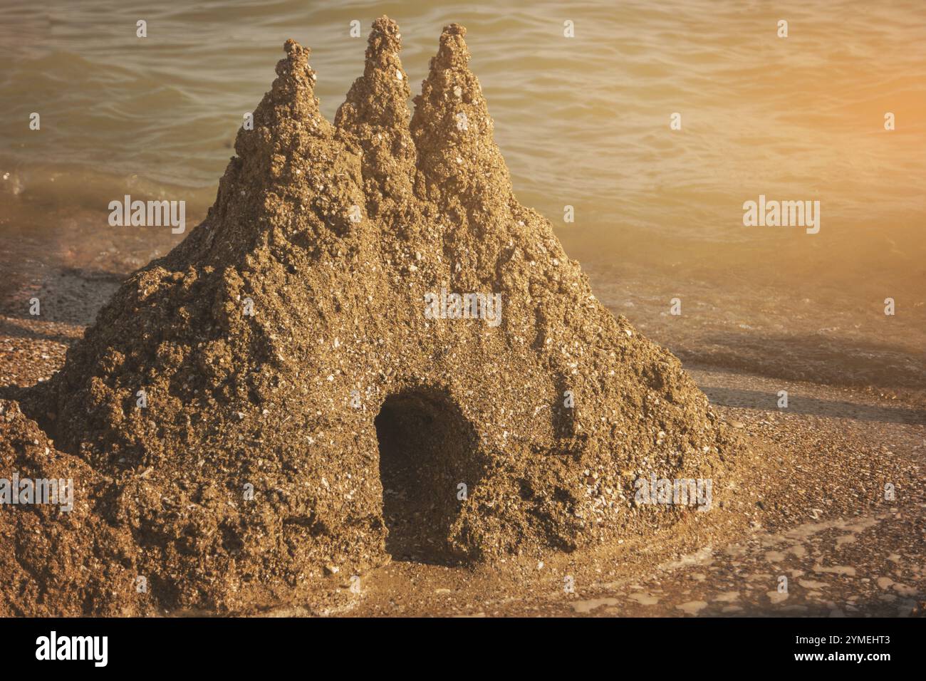 Sandcastle on a shore. Water, sand and light. Fragile work of art ...