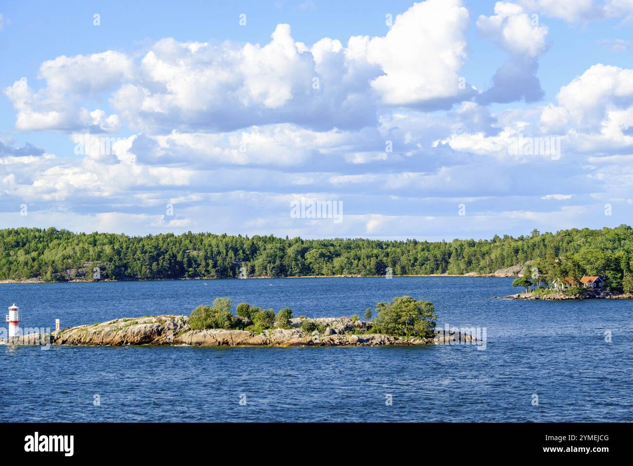 Small wooded island with lighthouse surrounded by blue water and cloudy ...