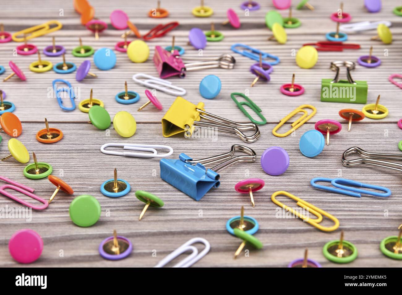 Set of various colorful paper clips on wooden desk. Many stationery ...