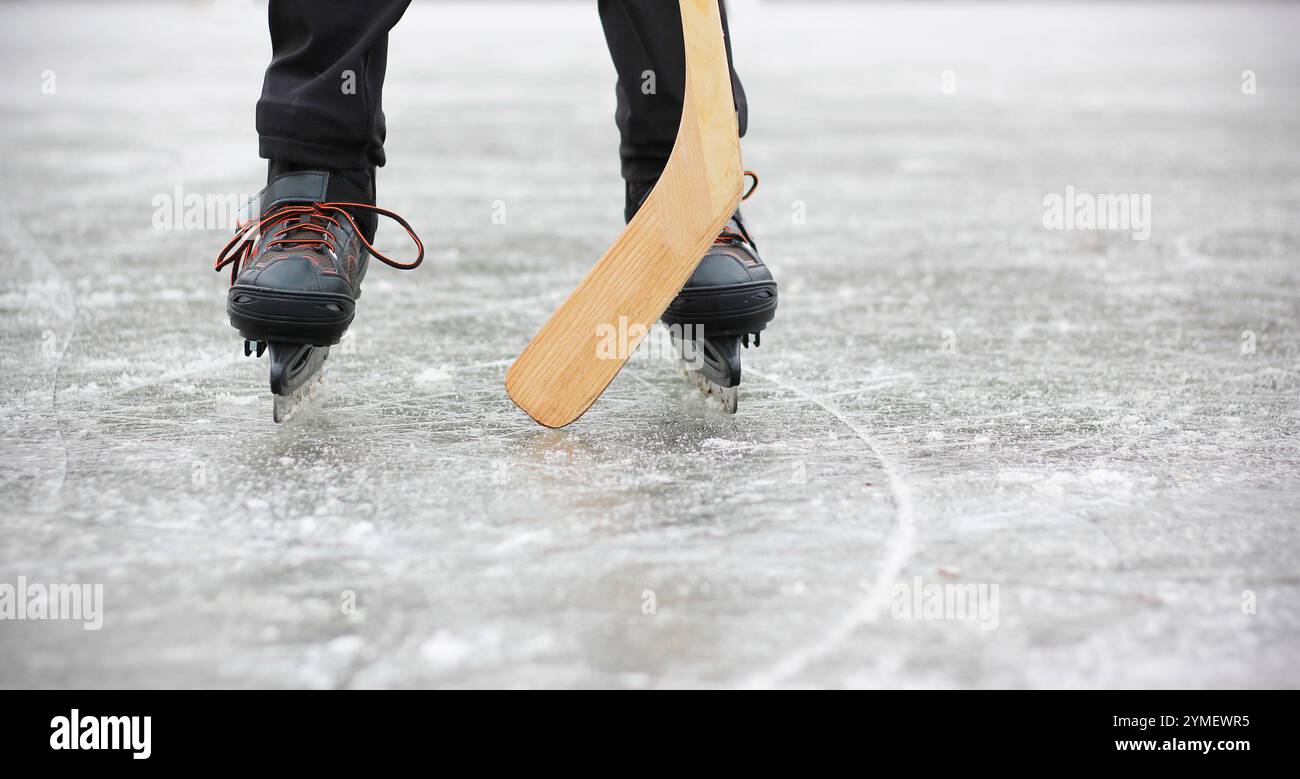 Ice skates and hockey stick close-up. Legs of a boy playing ice hockey ...