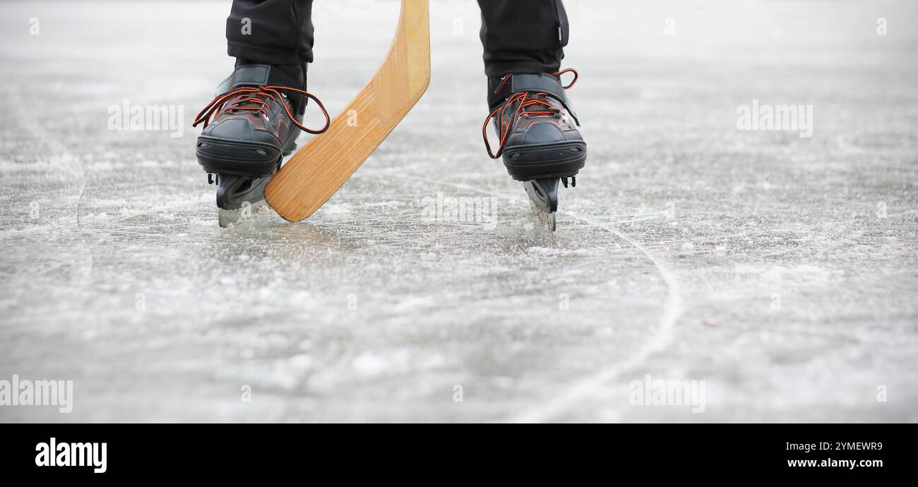 Ice skates and hockey stick close-up. Legs of a boy playing ice hockey ...