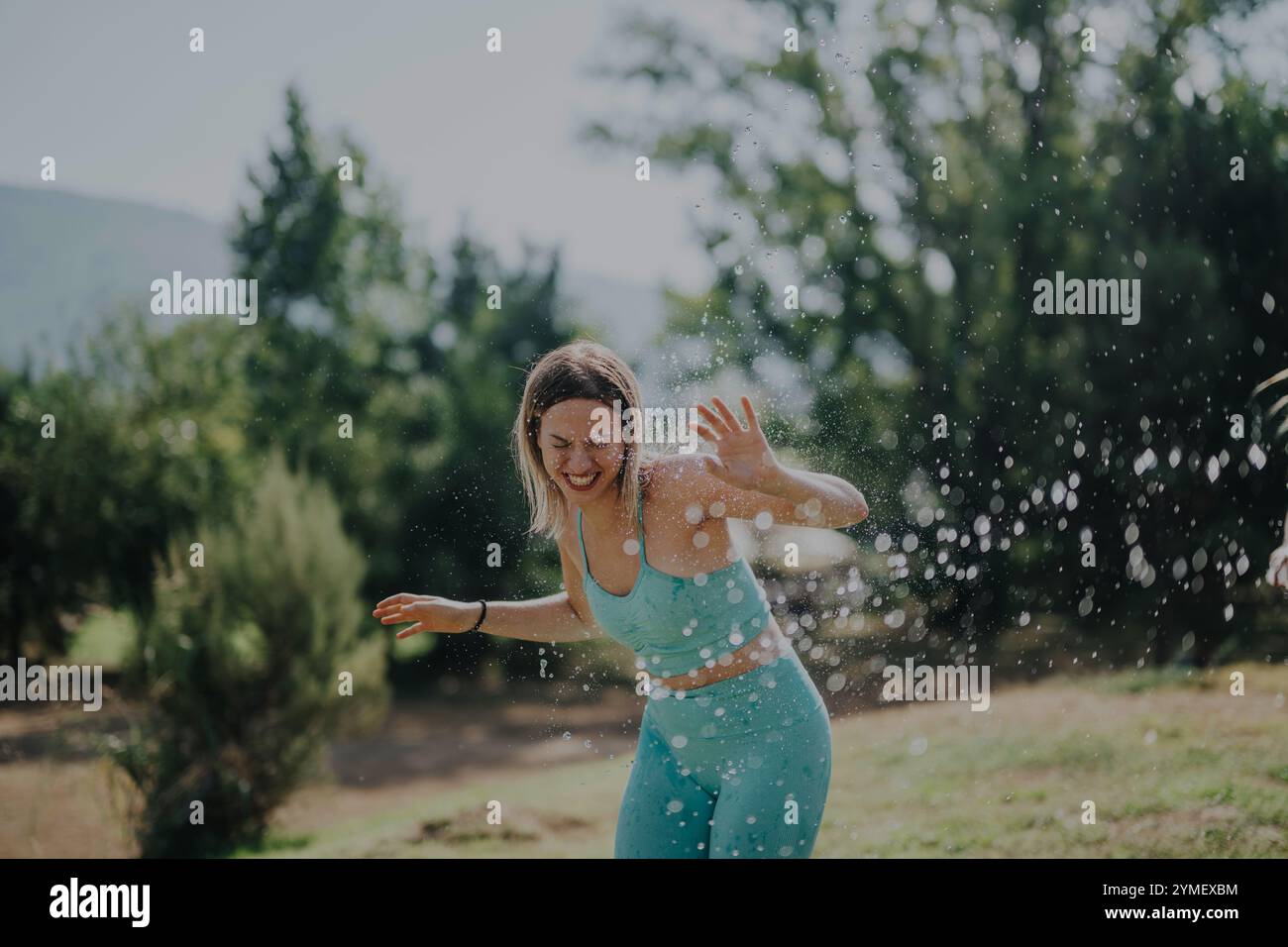 Young woman enjoying a refreshing splash of water outdoors Stock Photo ...