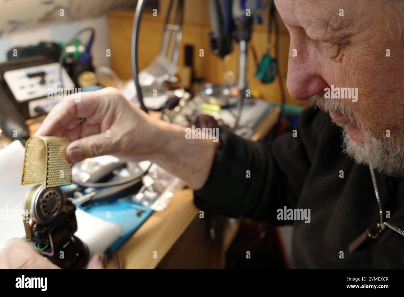 An old man repairs an equally old microphone. Repair instead of replace ...