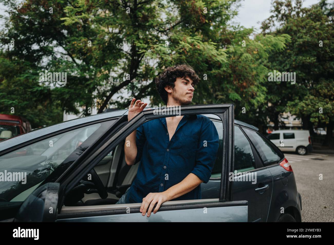 Man stepping out of car in a lush green parking area Stock Photo - Alamy