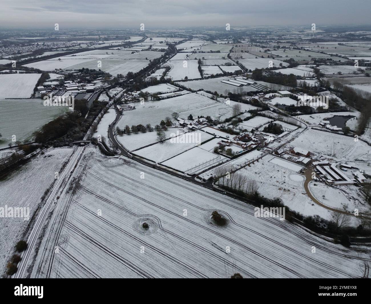 A snowy field with a few houses in the distance. The sky is cloudy and ...