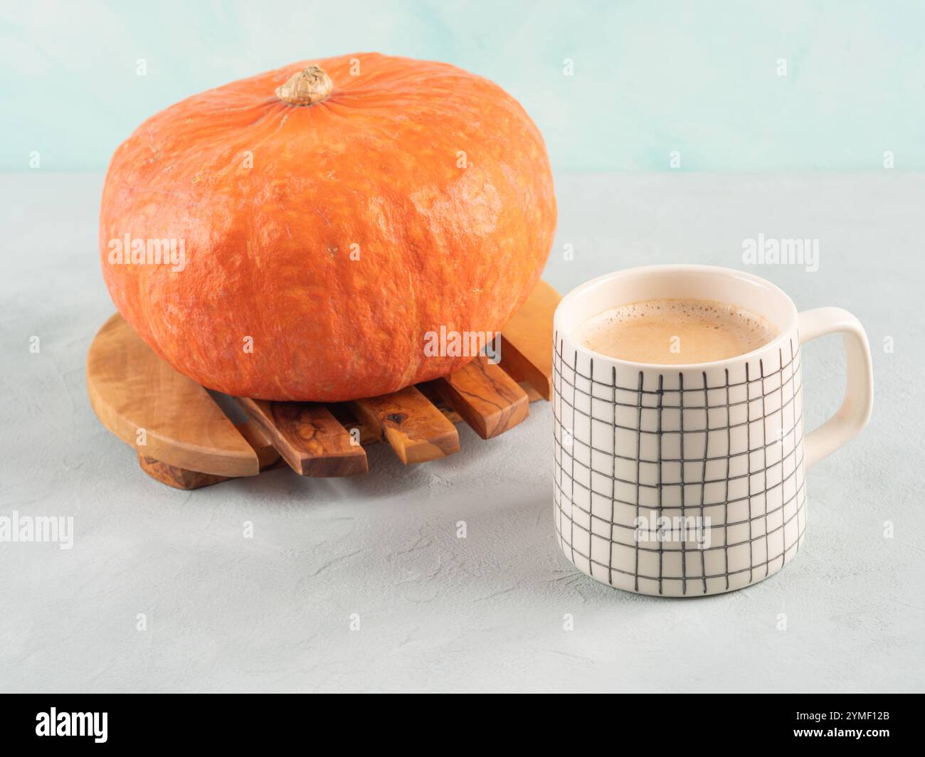 Pumpkin spiced latte coffee on turquoise background with orange squash ...