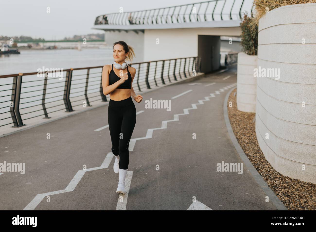 In the early morning light, a fit young woman runs gracefully along a ...