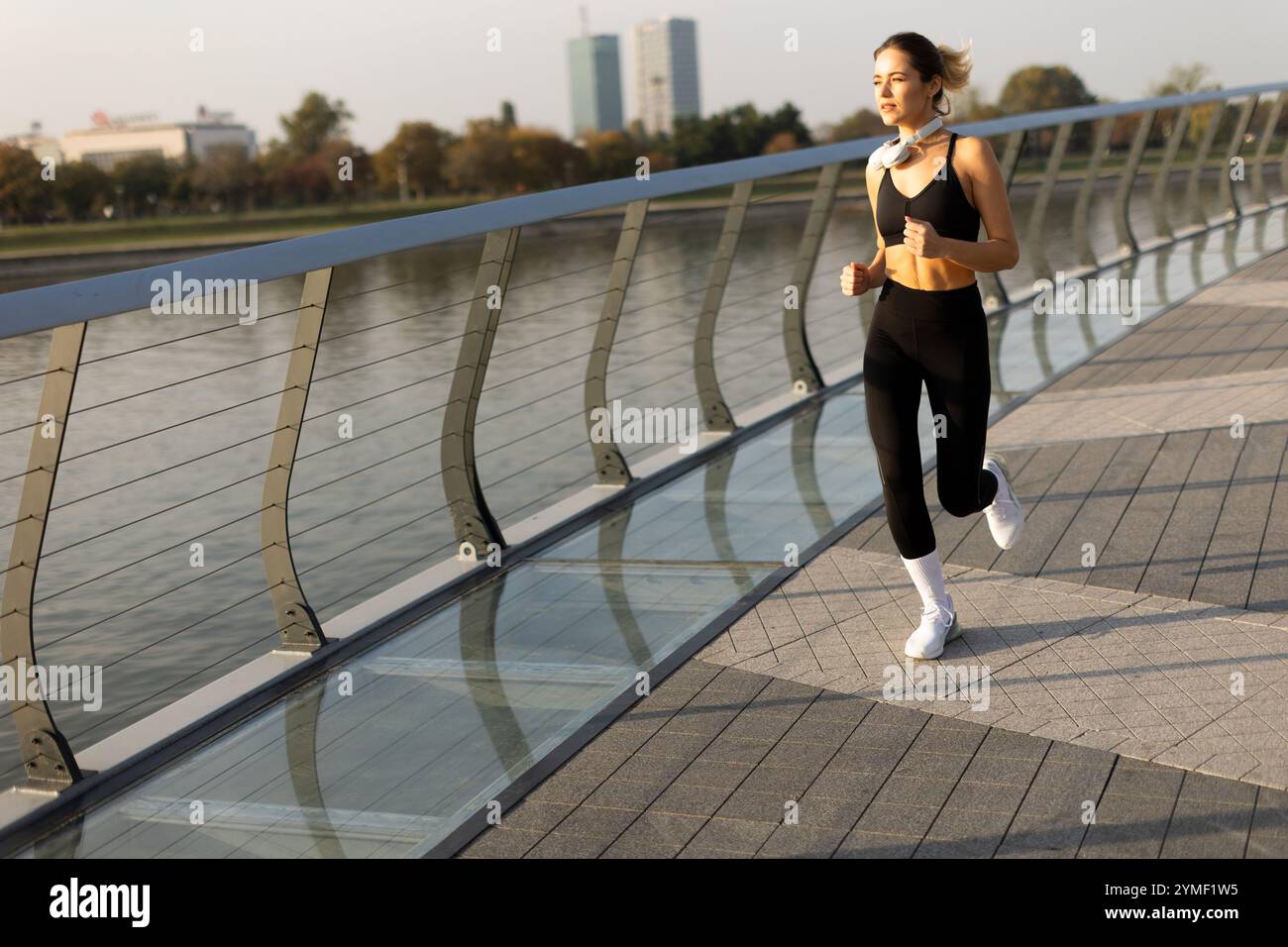 In the early morning light, a fit young woman runs gracefully along a ...