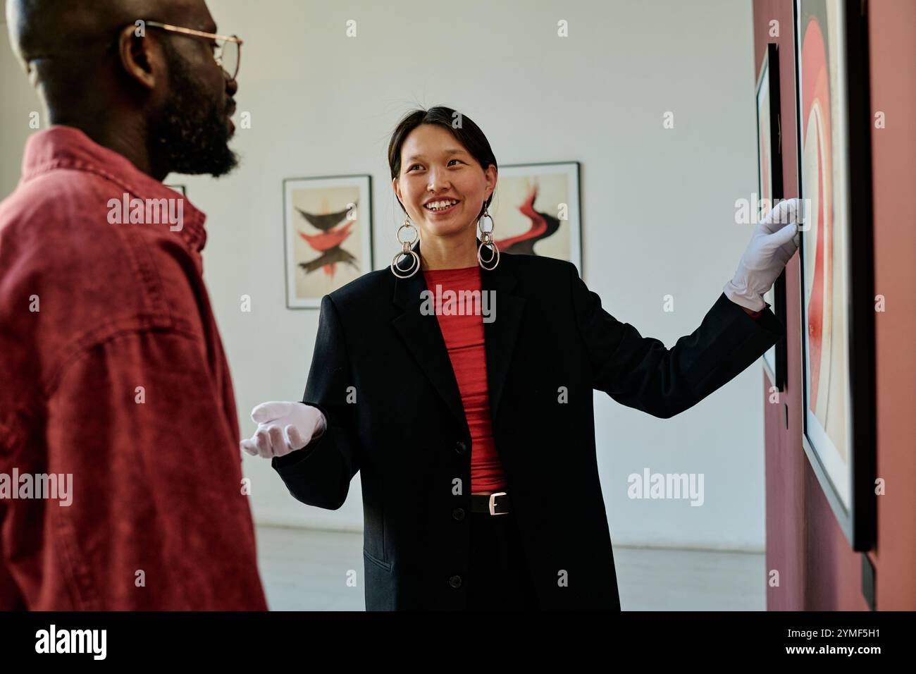 Art curator explaining contemporary art pieces to visitor while ...