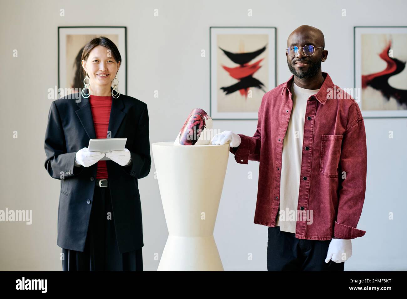 Two art curators standing in gallery next to an abstract sculpture ...