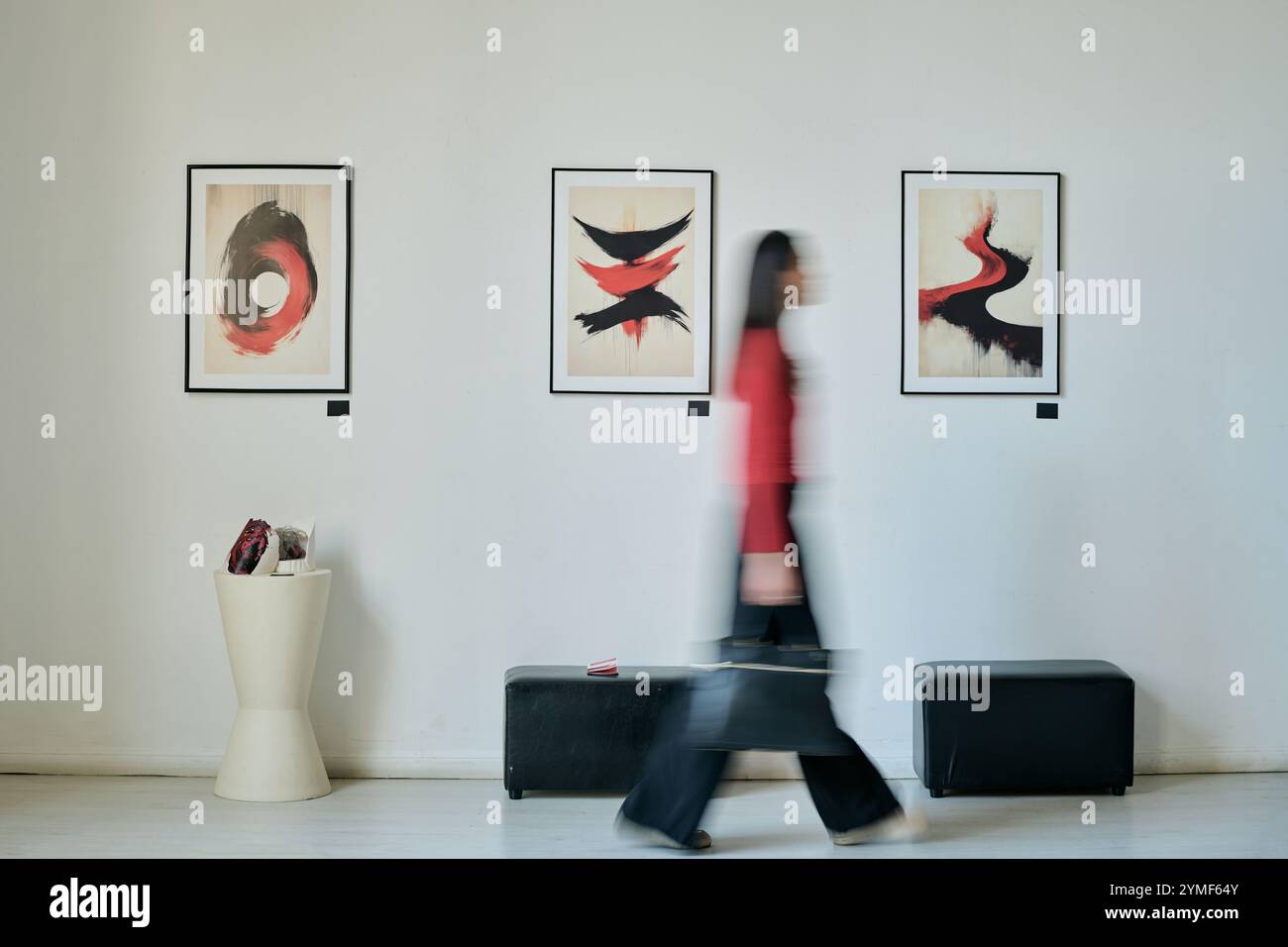 Individual with blurred figure walking past modern art pieces in ...