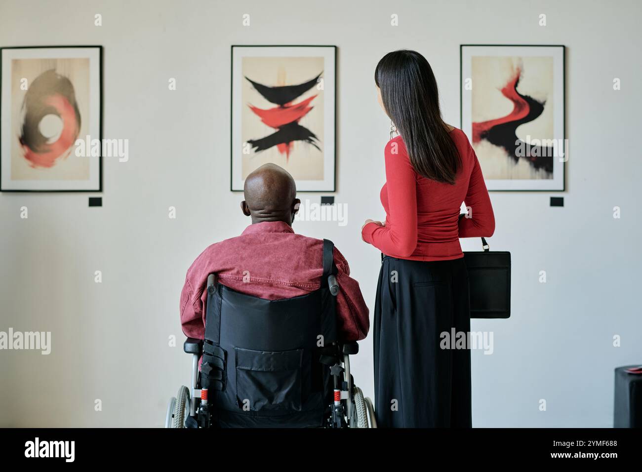 Two people observing abstract artworks displayed on wall in modern art ...