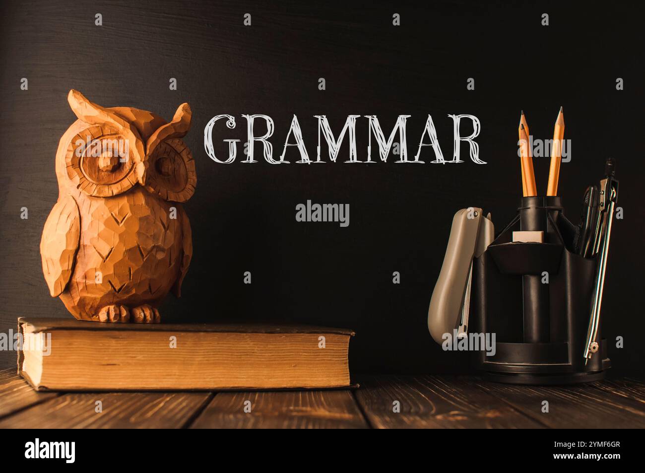 Wooden owl sits on top of a stack of books. The owl is surrounded by ...