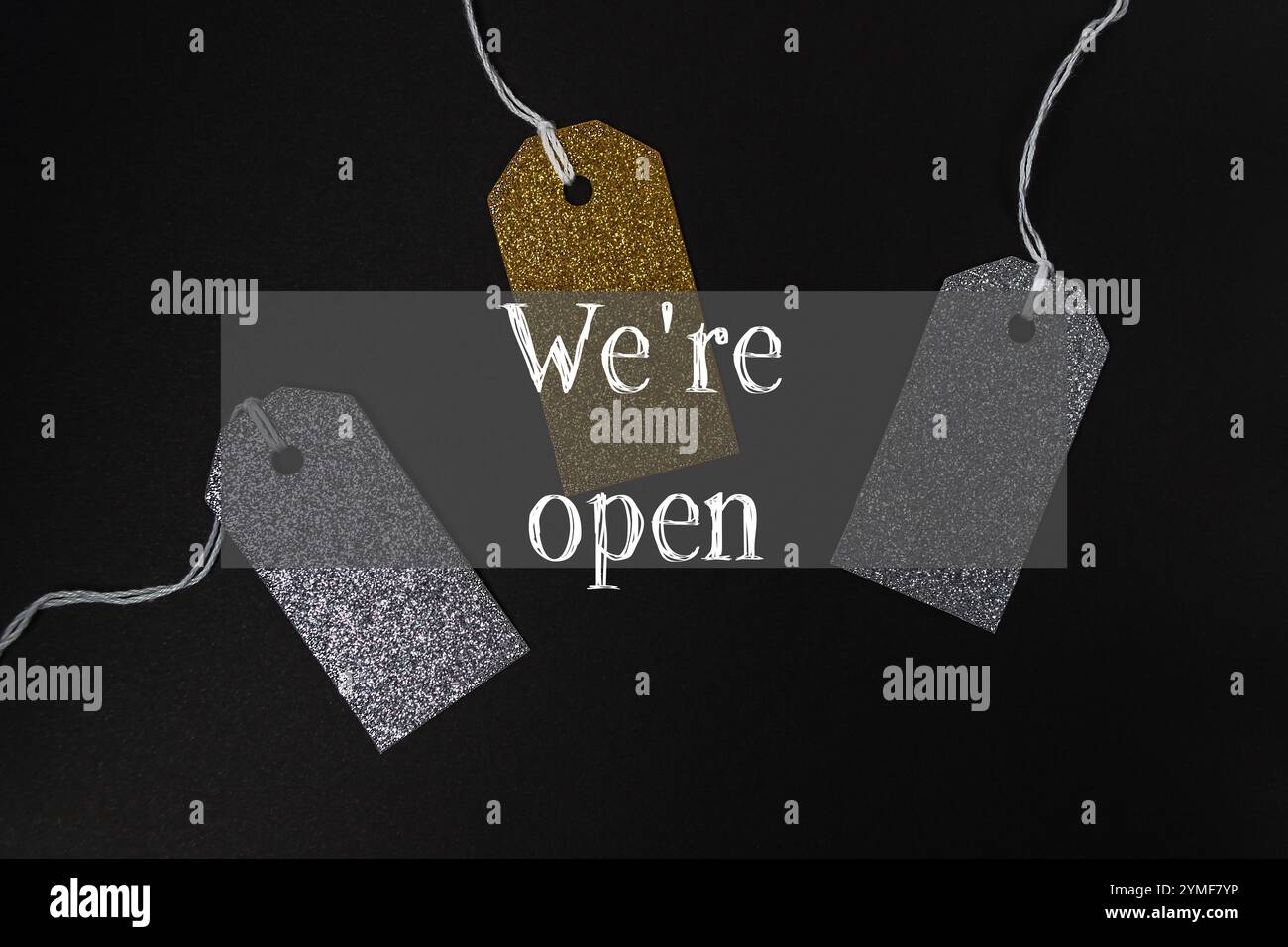 Three tags with gold glitter hanging from a string with the words we're ...