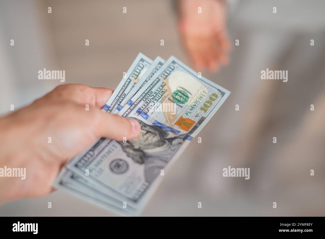 A hand passes hundred dollar bills to another person Stock Photo - Alamy