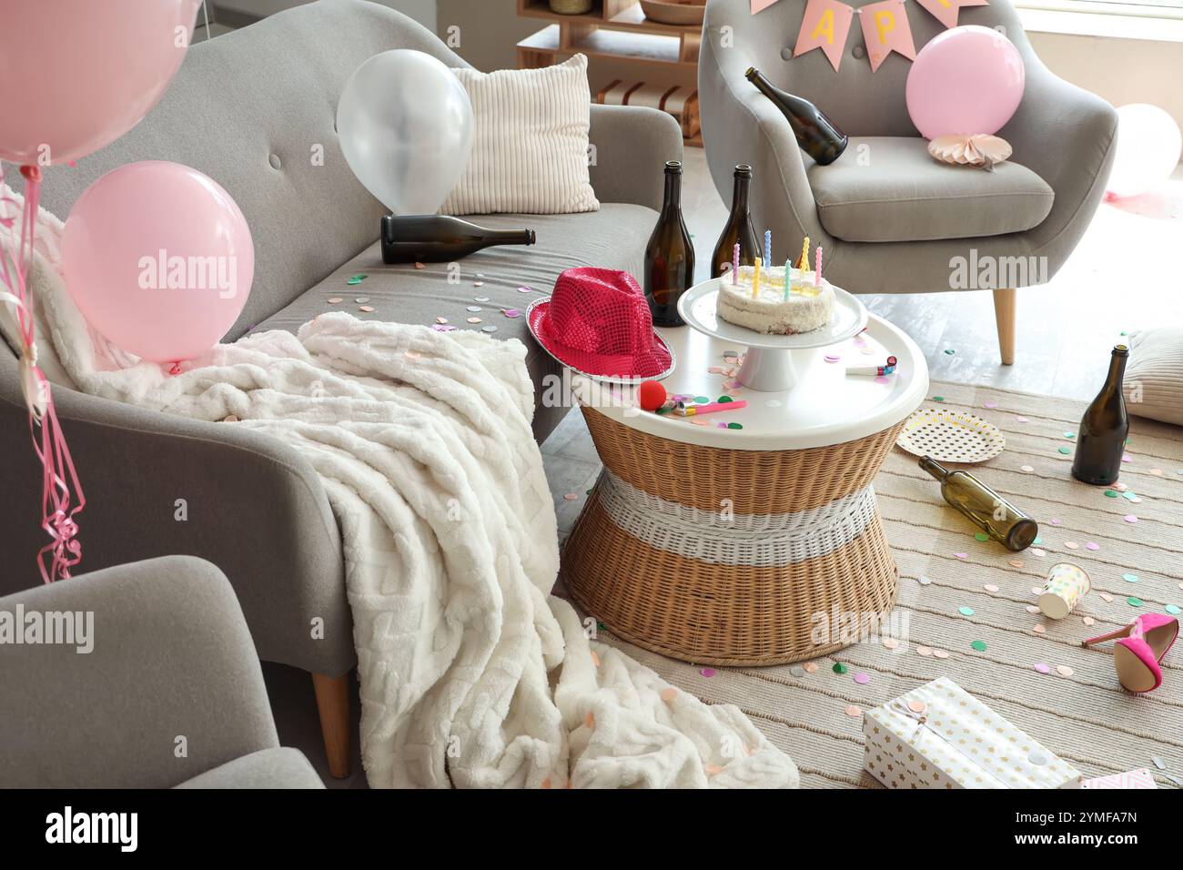 Birthday cake with bottles and party decor on table in messy living ...