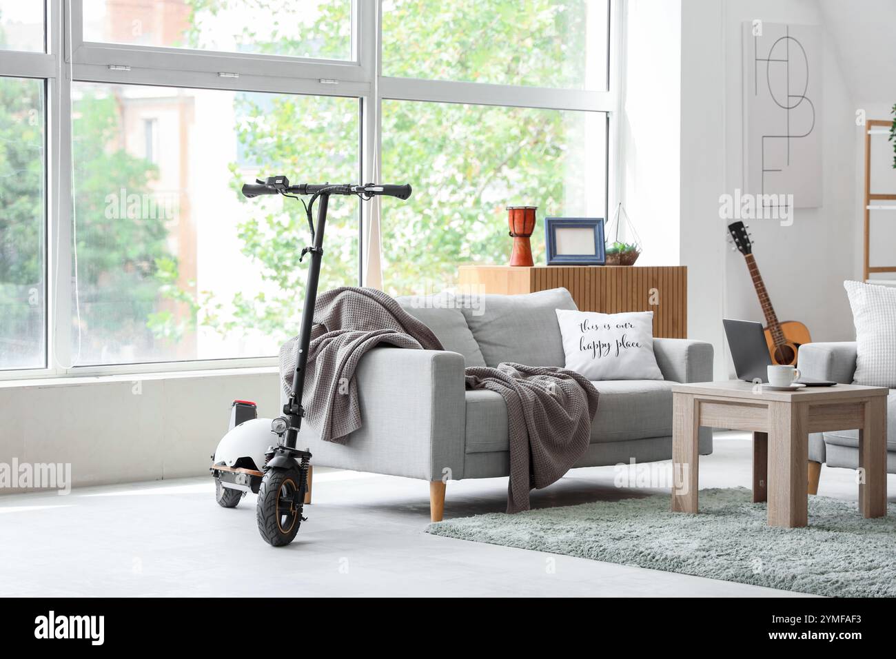 Interior of light living room with electric scooter, sofa and table ...