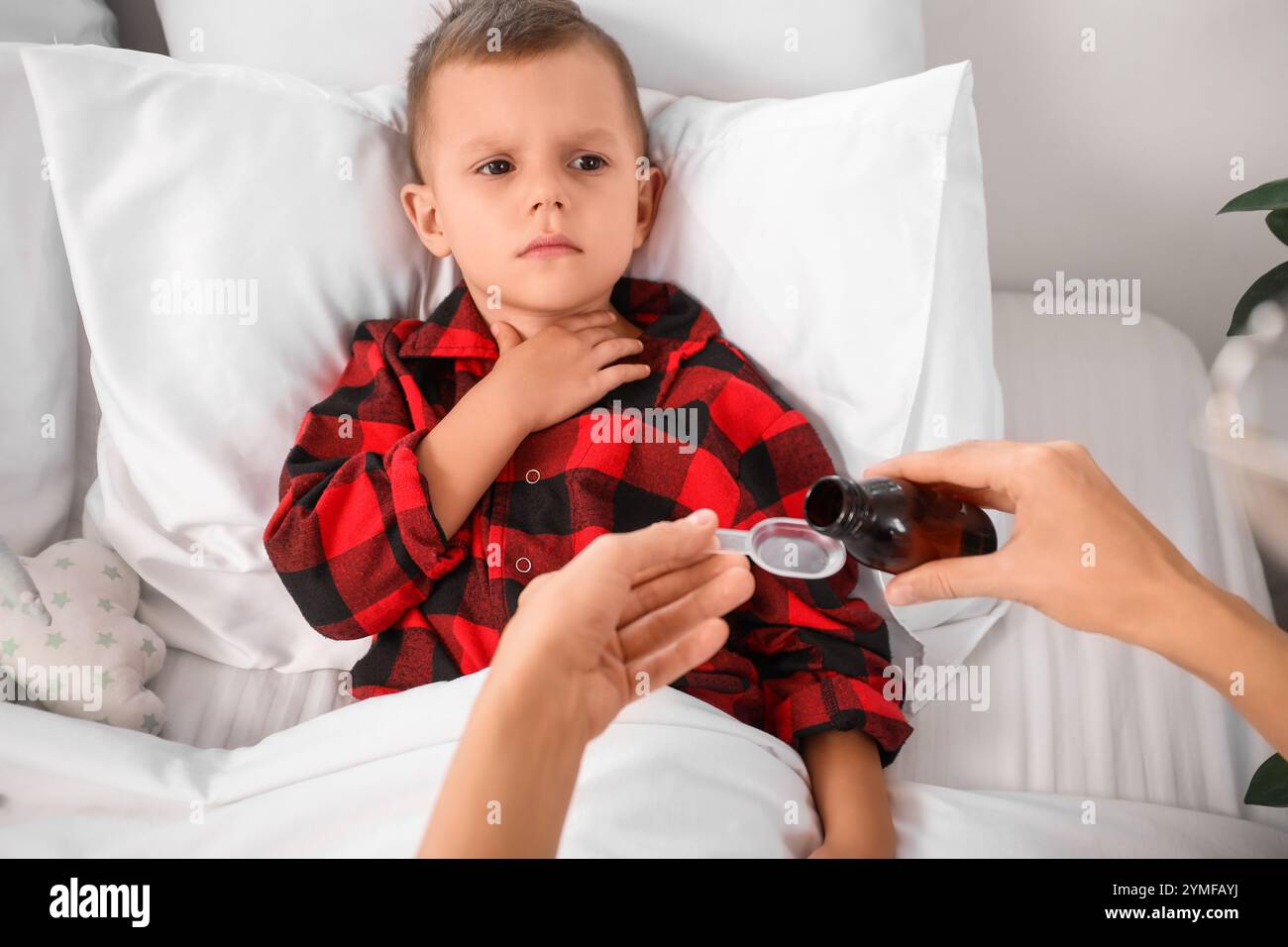 Sick little boy with his mother pouring couch syrup in bedroom Stock ...