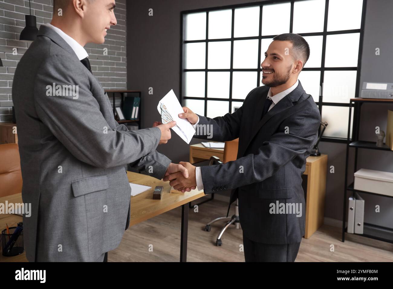 Young business men with bribe shaking hands in office. Corruption ...
