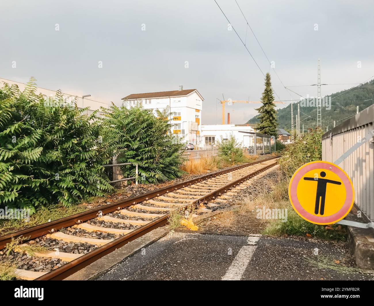 A railroad track with a yellow sign that says Do not enter and a person ...