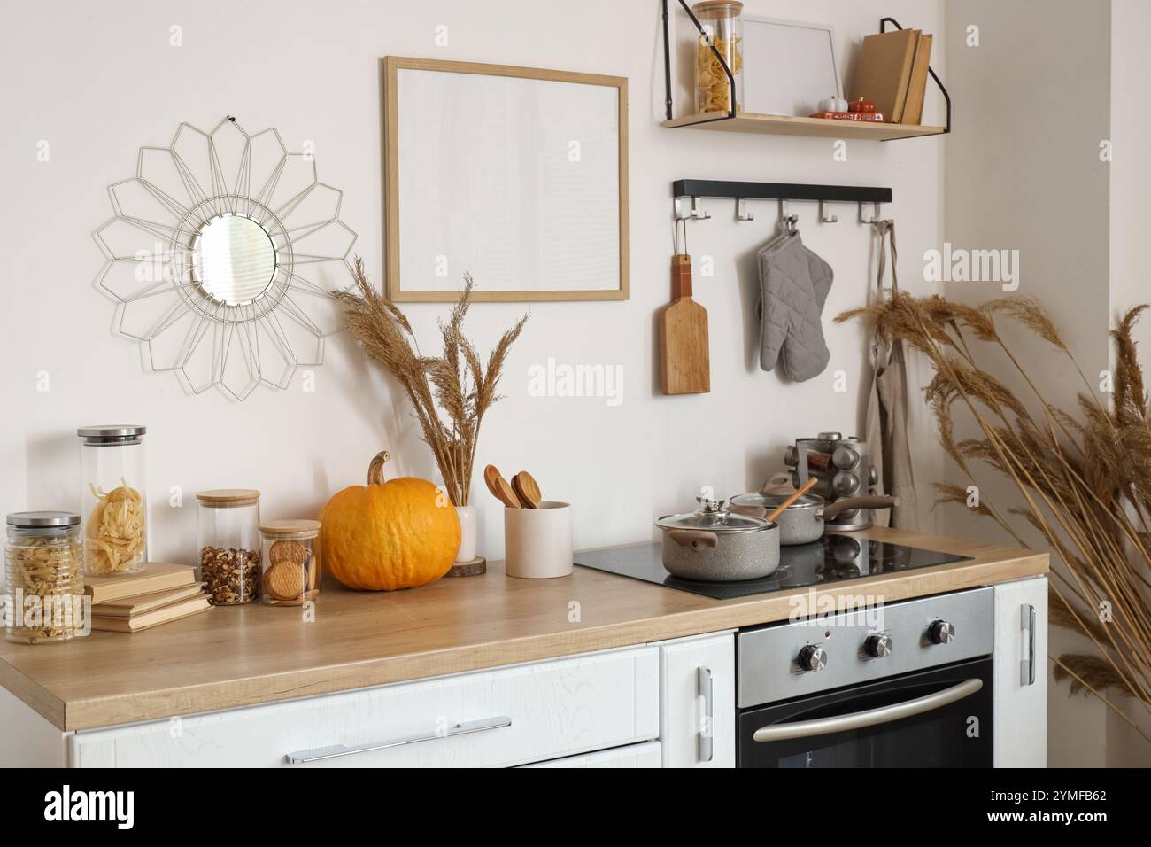 Pumpkin with pampas grass and food on counter in light kitchen interior ...