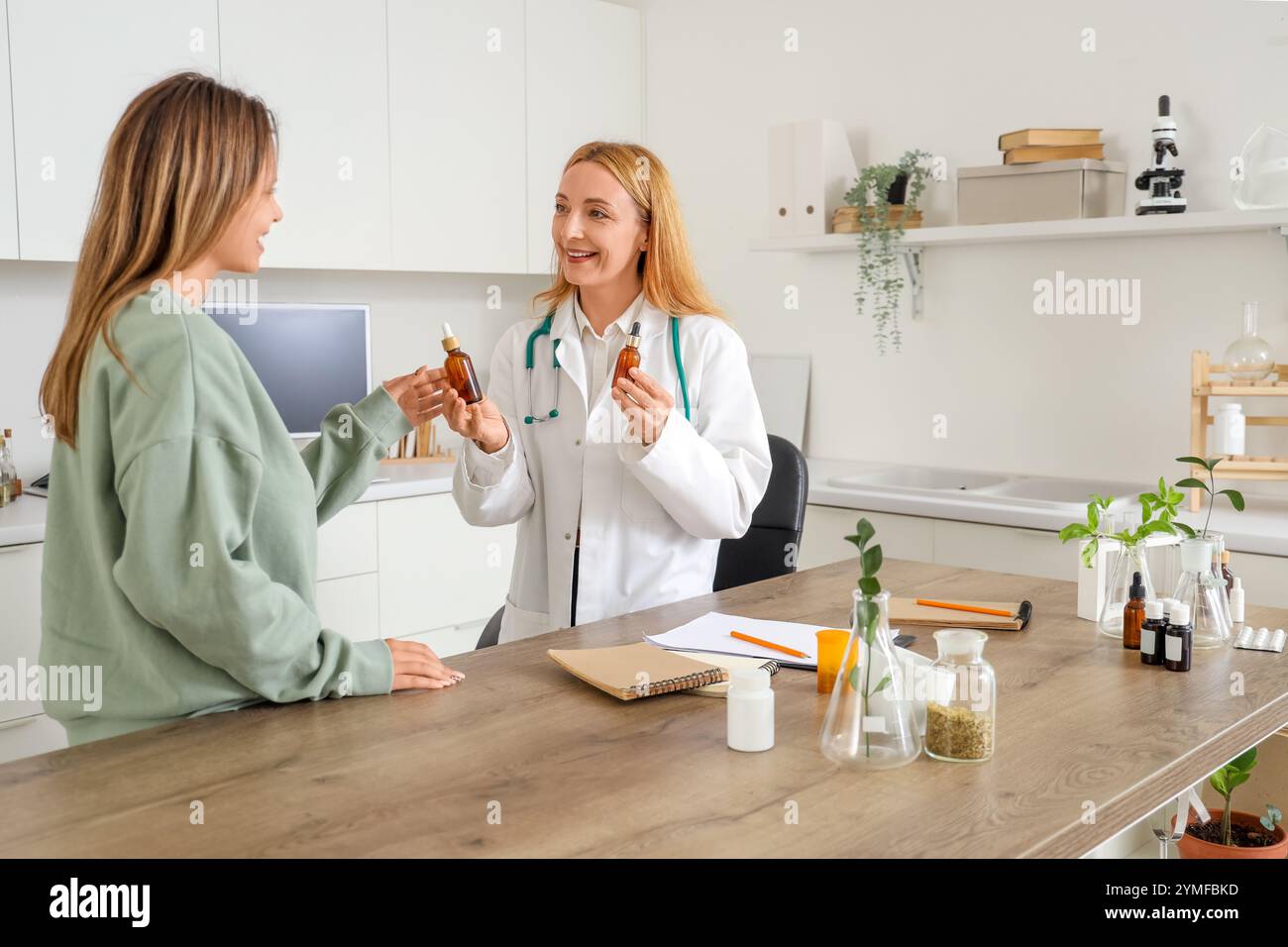 Female homeopathic doctor giving dropper bottles to patient in office ...