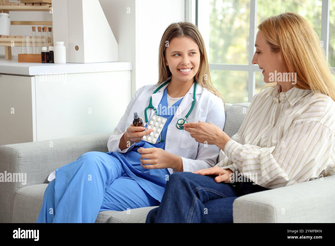 Female homeopathic doctor giving remedy to patient on sofa in office ...