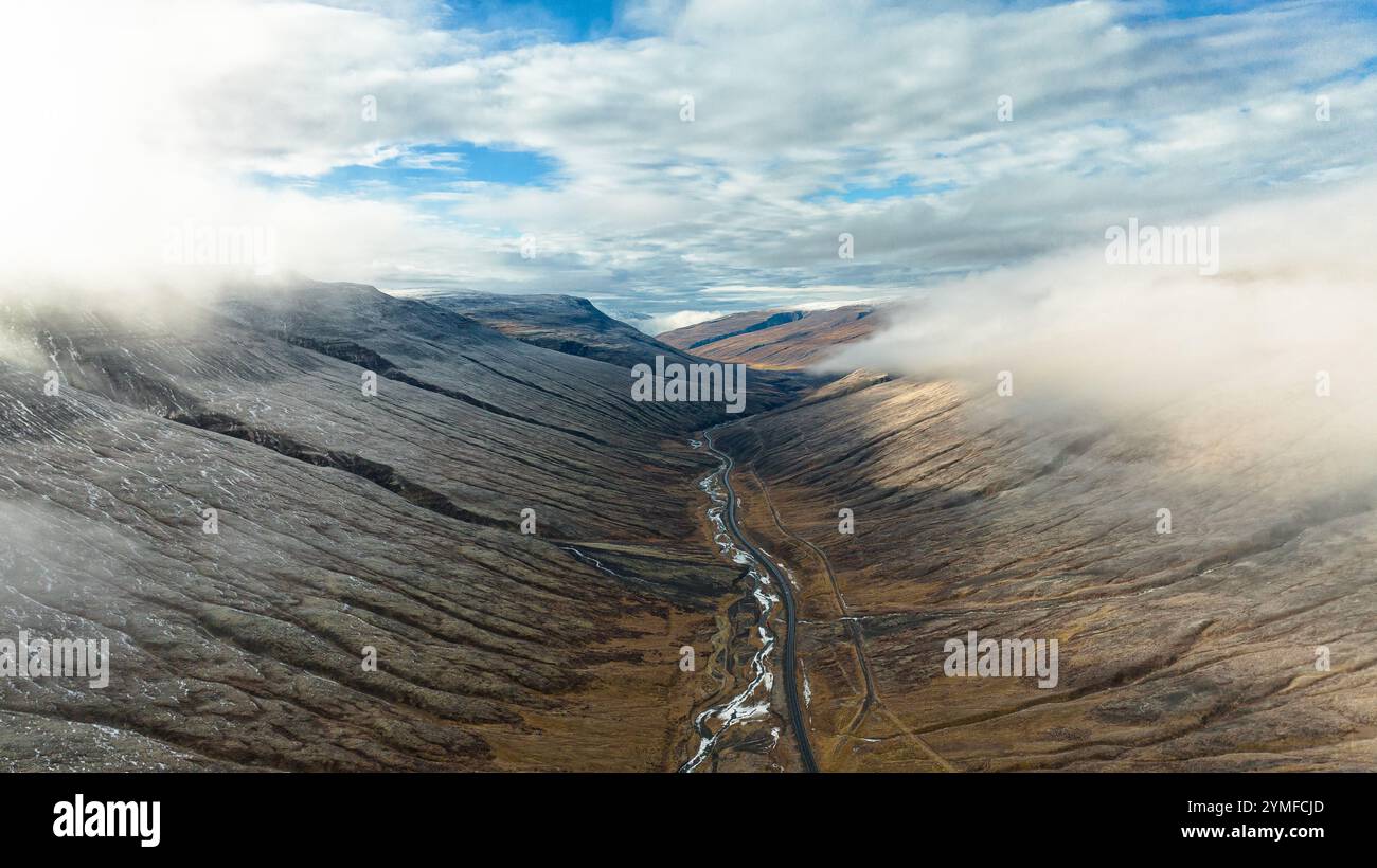 Asphalt road and frozen river between hills against fog. Majesty of ...