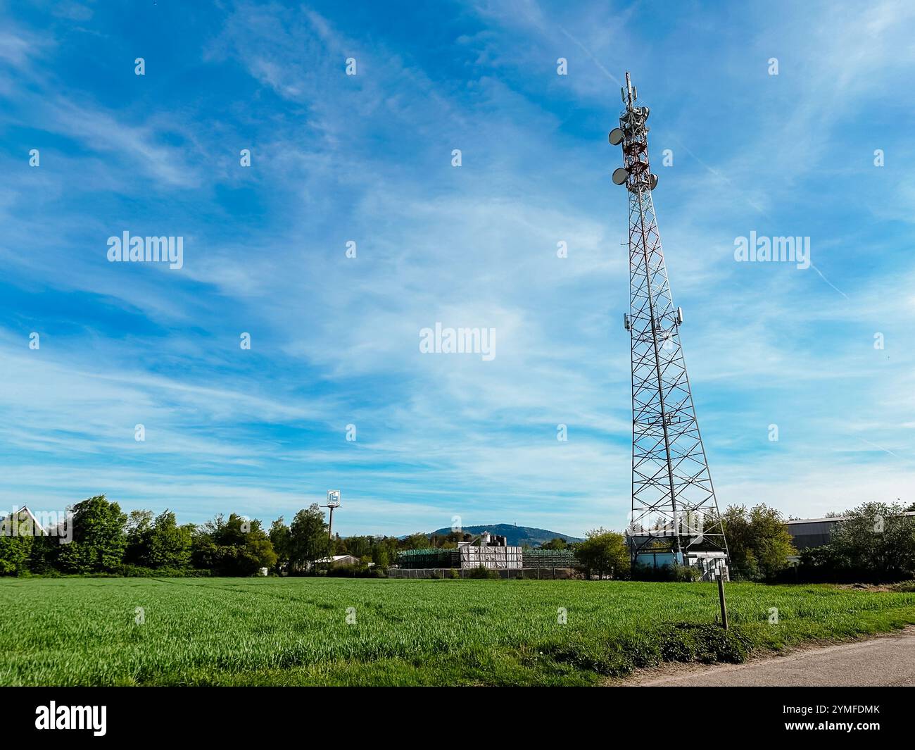 A tall tower with a white top stands in a field, featuring antennas for ...