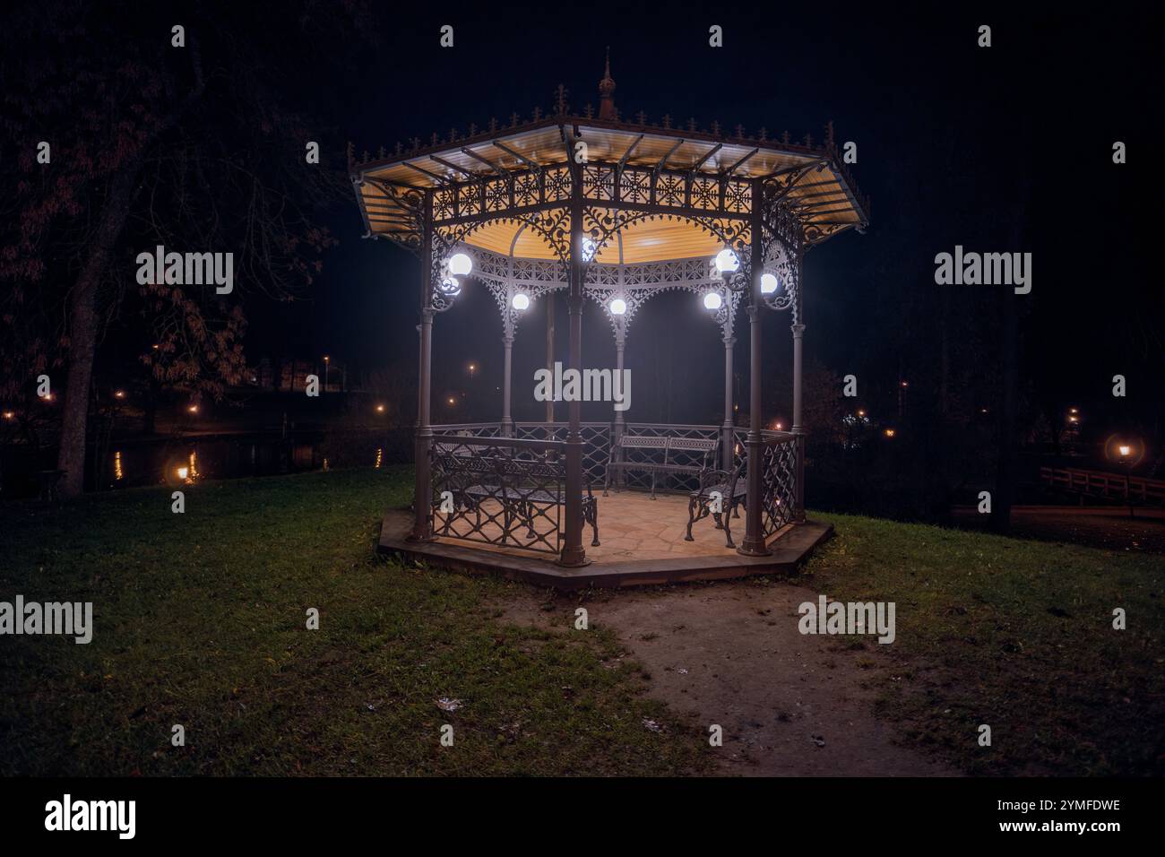 A beautifully lit gazebo with intricate metalwork standing in a quiet ...
