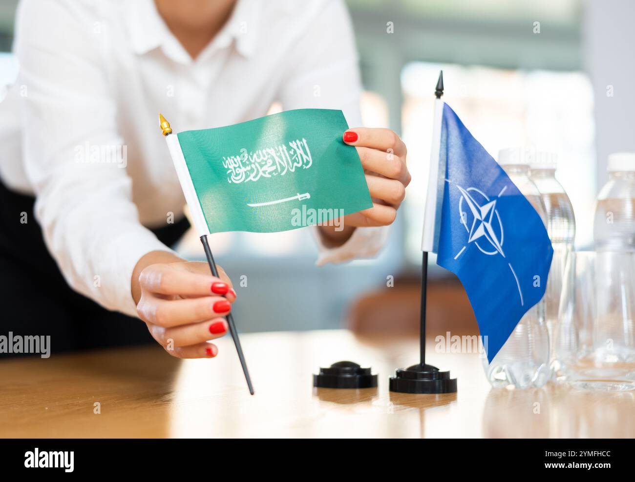 Female secretary places flags of the NATO (OTAN) and Saudi Arabia on ...