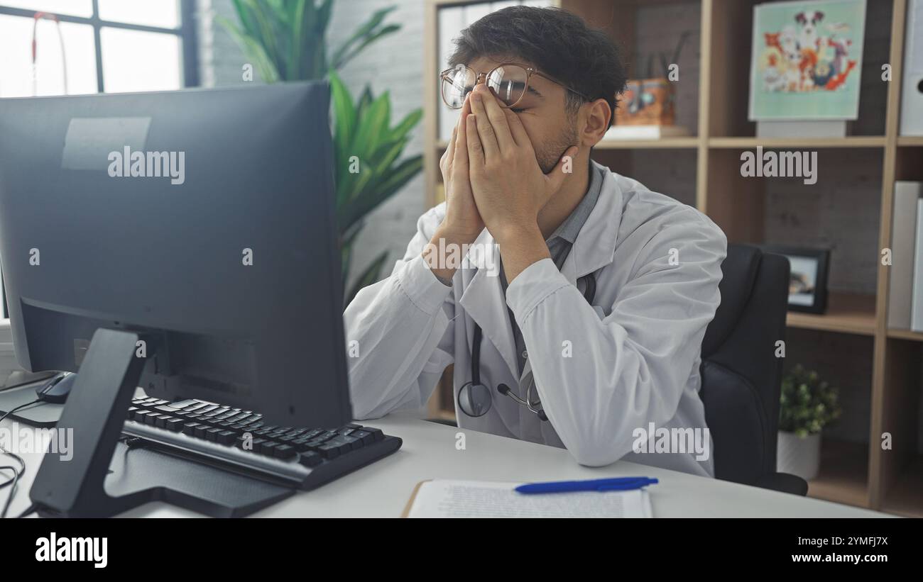 A stressed young arab man in medical attire experiences burnout at his ...