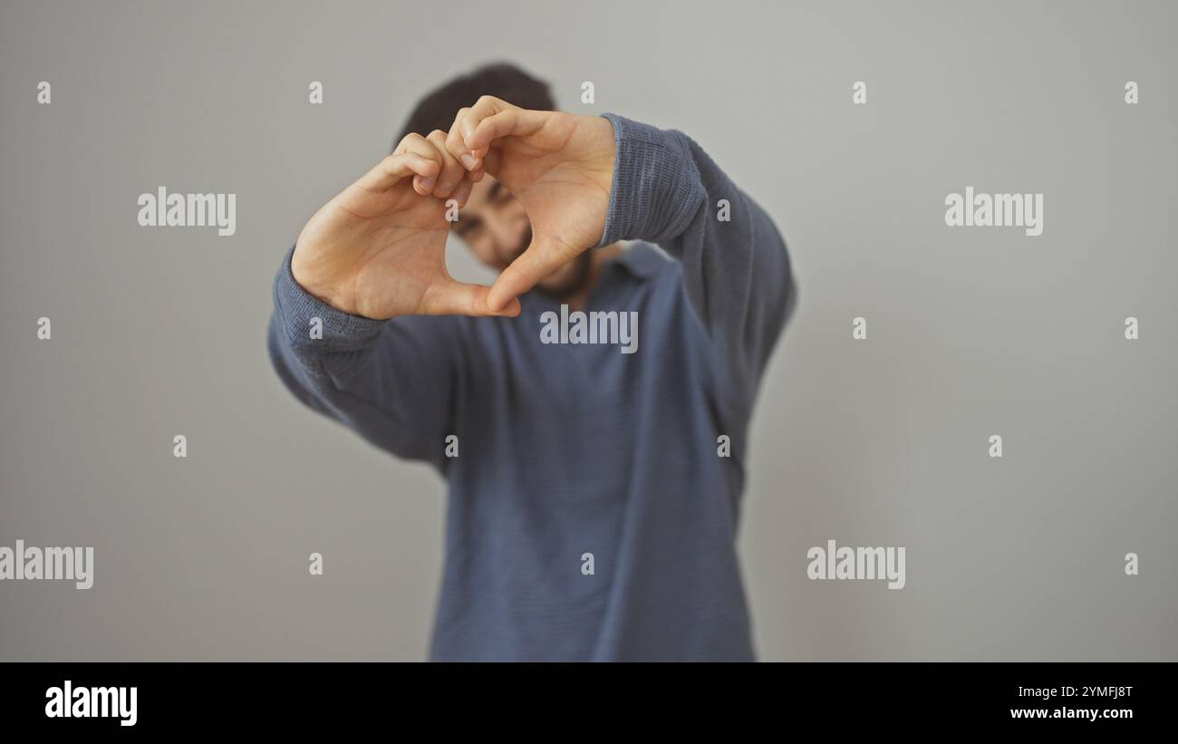 Handsome man forms heart shape with hands against isolated white ...