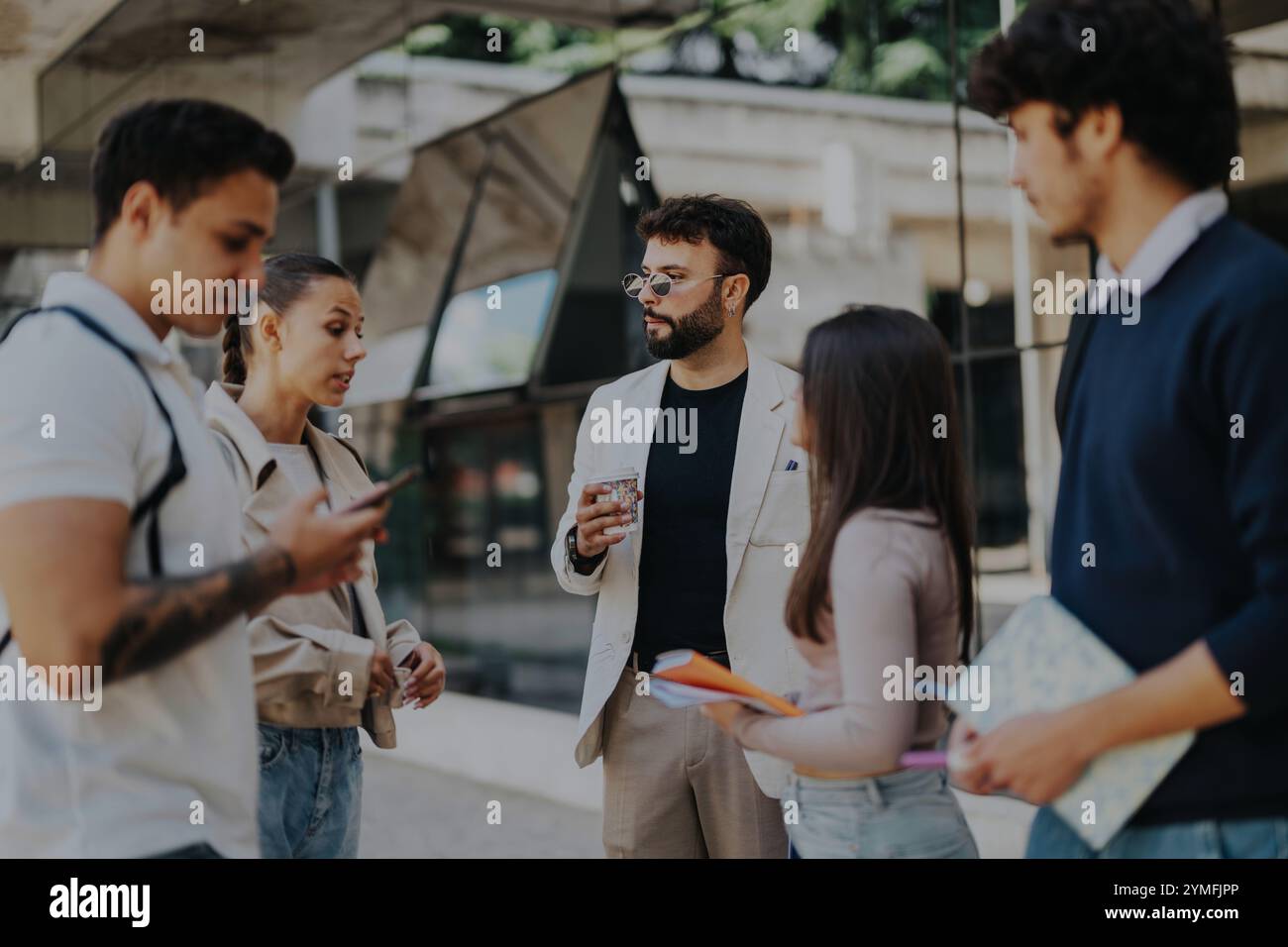 University students engaging with professor in outdoor campus setting ...