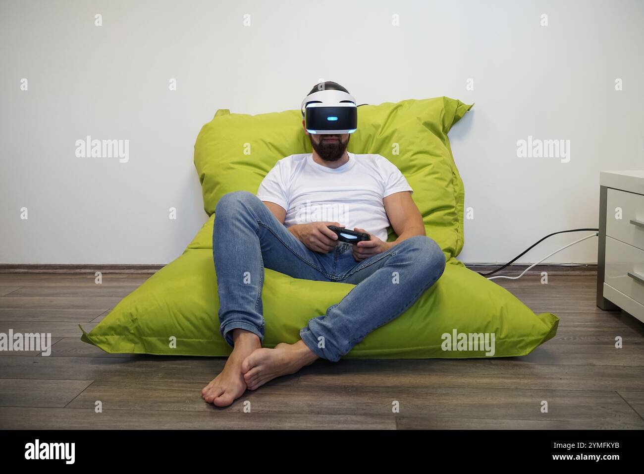Man wearing VR headset, sitting comfortably on green bean bag while ...