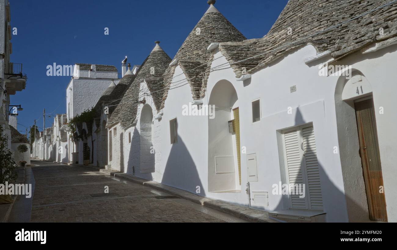 A picturesque street in alberobello, italy, features traditional white ...