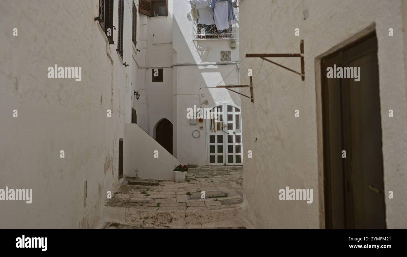 Picturesque narrow alley with white-washed buildings in ostuni, puglia ...