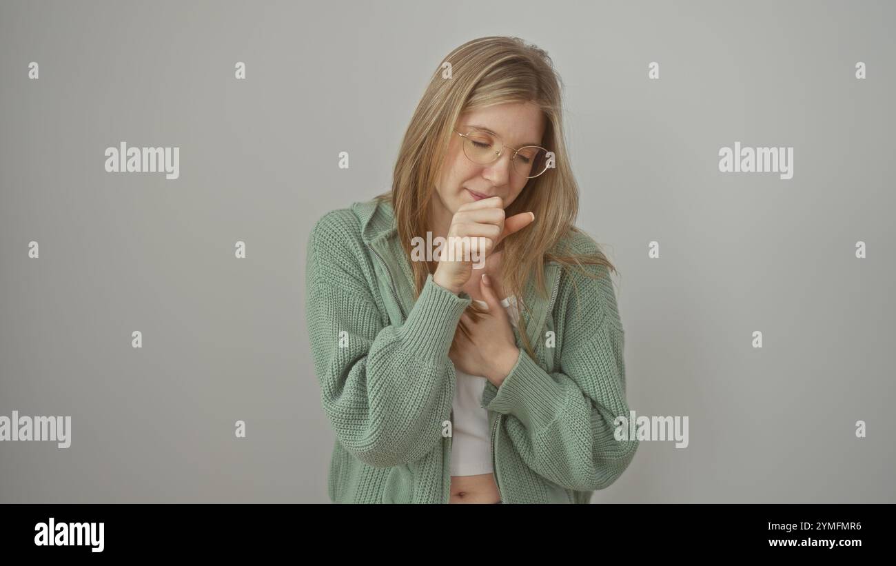 A young blonde woman coughing into her hand, isolated on a white ...