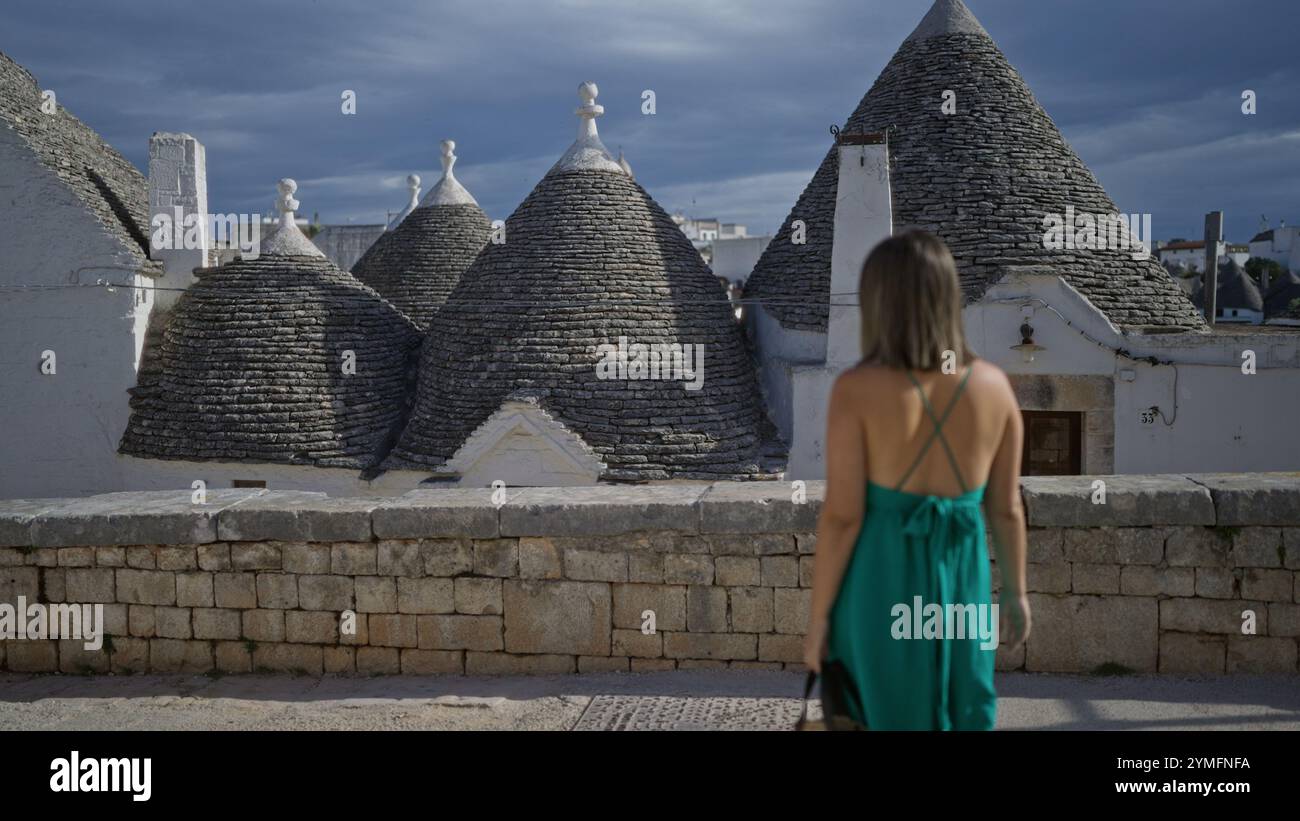 A young hispanic woman observes the iconic trulli rooftops in the old ...