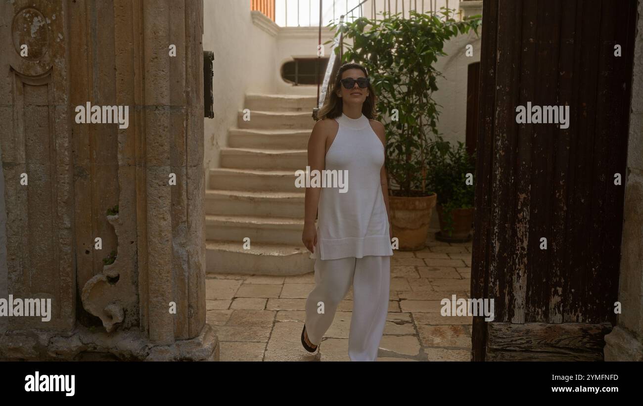 A beautiful young hispanic woman walks through the old town streets of ...