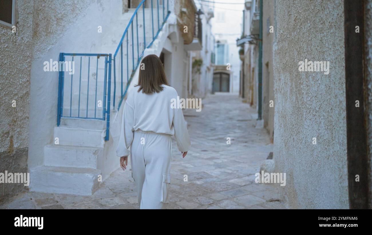 A young hispanic woman walks through the narrow, picturesque streets of ...