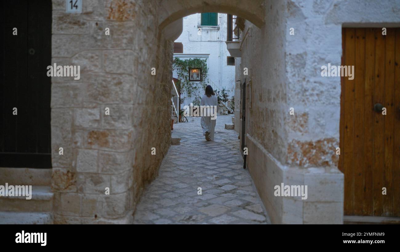 A young hispanic woman strolls through a historic street in polignano a ...