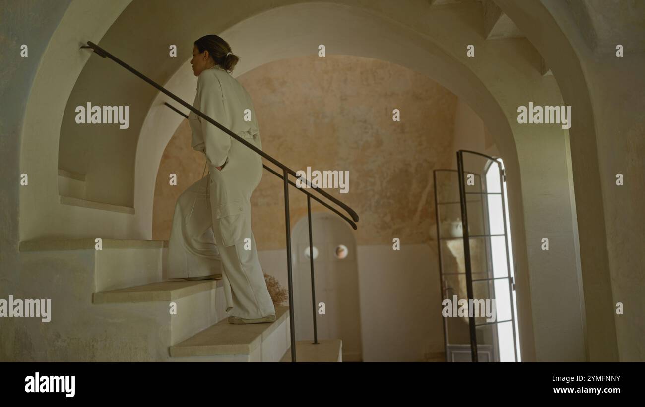 A beautiful young hispanic woman ascends an indoor staircase in a ...
