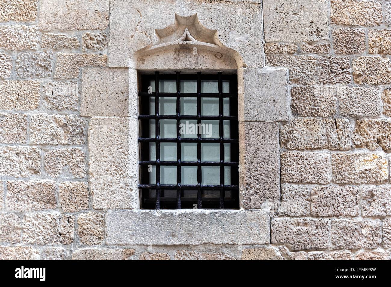 Rectangular window with black colored metal grille on an old beige ...