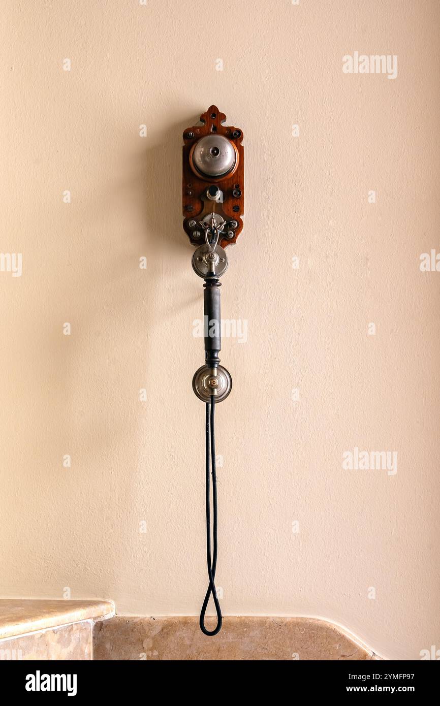 Antique telephone set with handset and bell hanging in a room on a pink ...