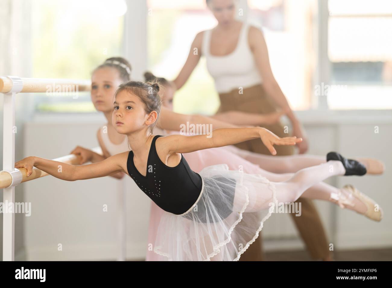 Woman teacher corrects girls in arabesque movement Stock Photo - Alamy