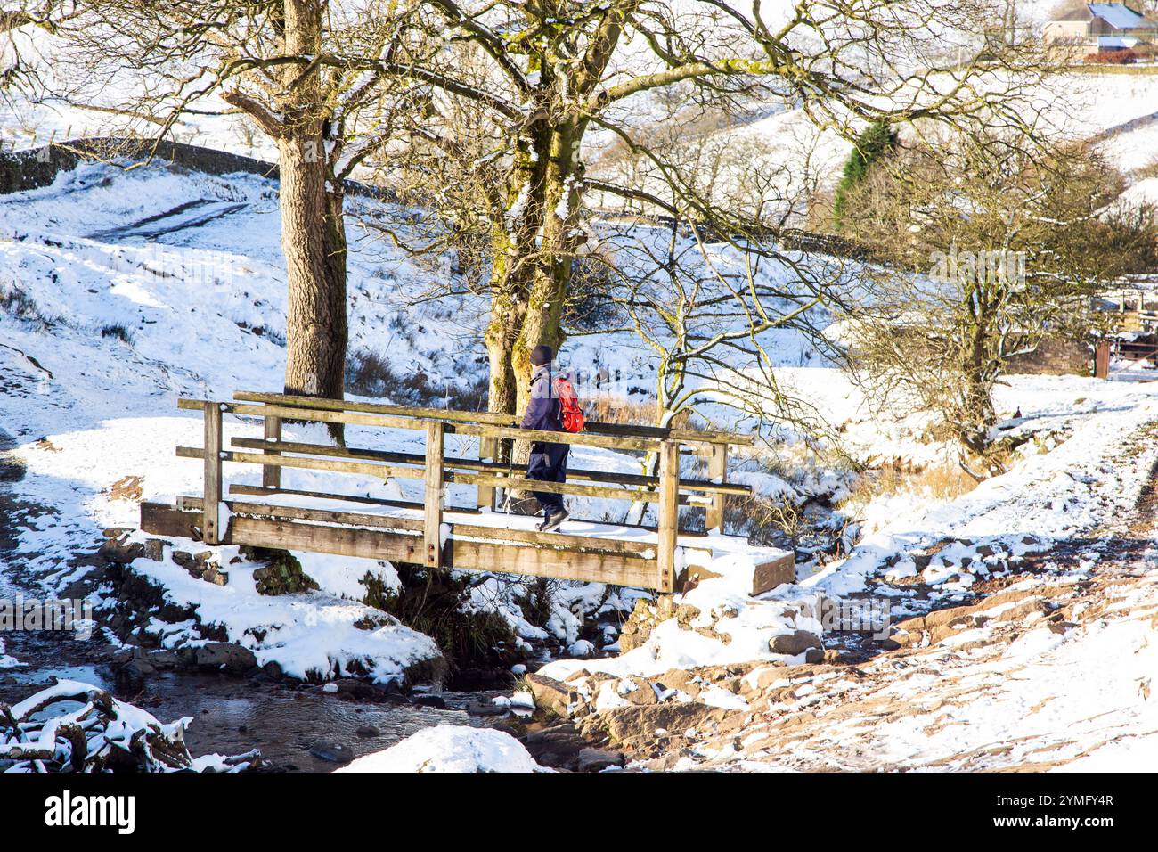 Man walking over wooden footbridge in snow covered landscape hi-res ...