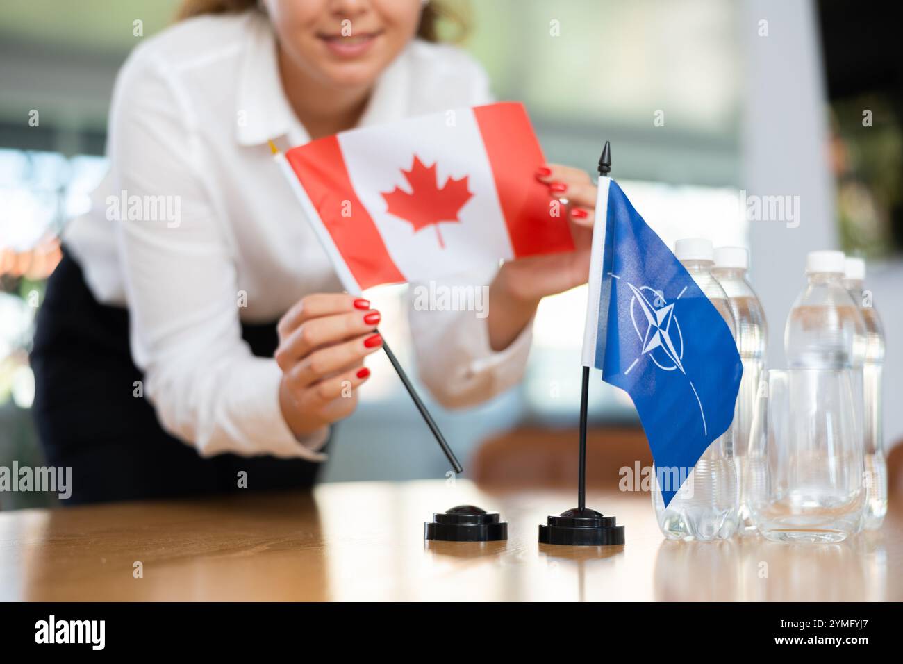 Female secretary places flags of the NATO (OTAN) and Canada on the ...