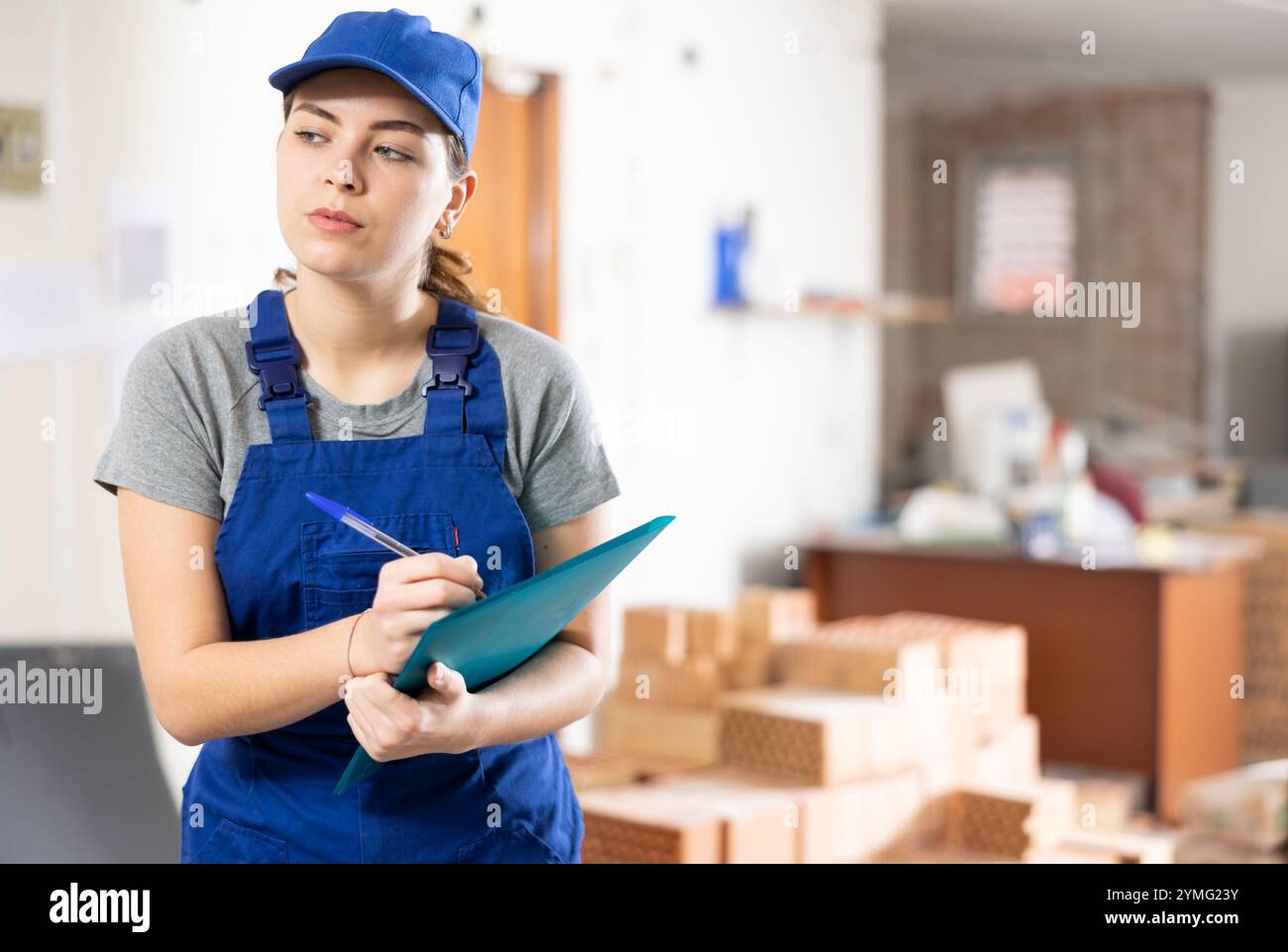 Female contractor checking blueprints and taking notes at building site ...